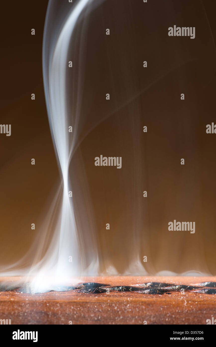 Burning incense smoke drifting whirling into a darkened room from exit ...