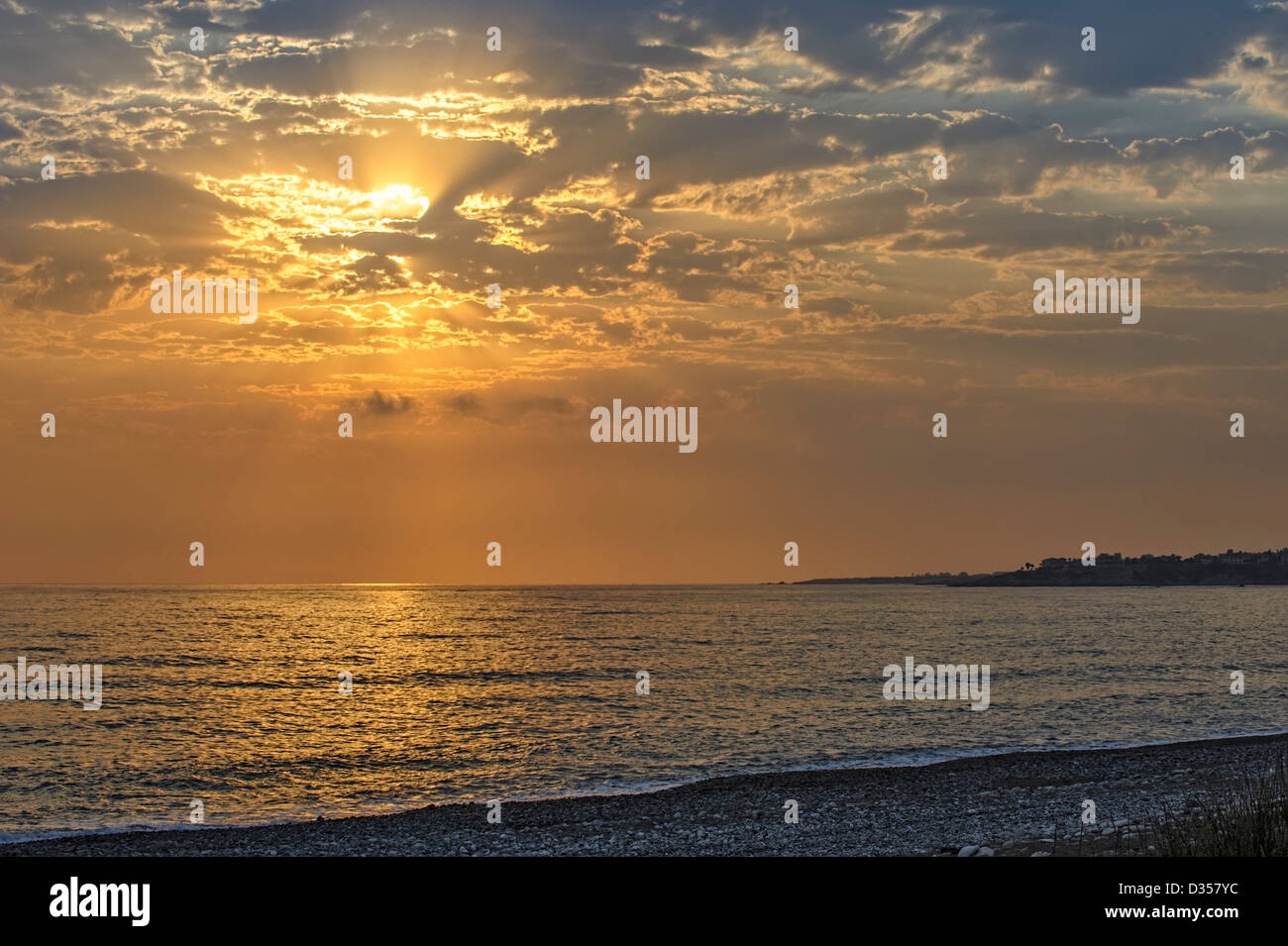 Sunset over the sea and pebble beach Stock Photo - Alamy