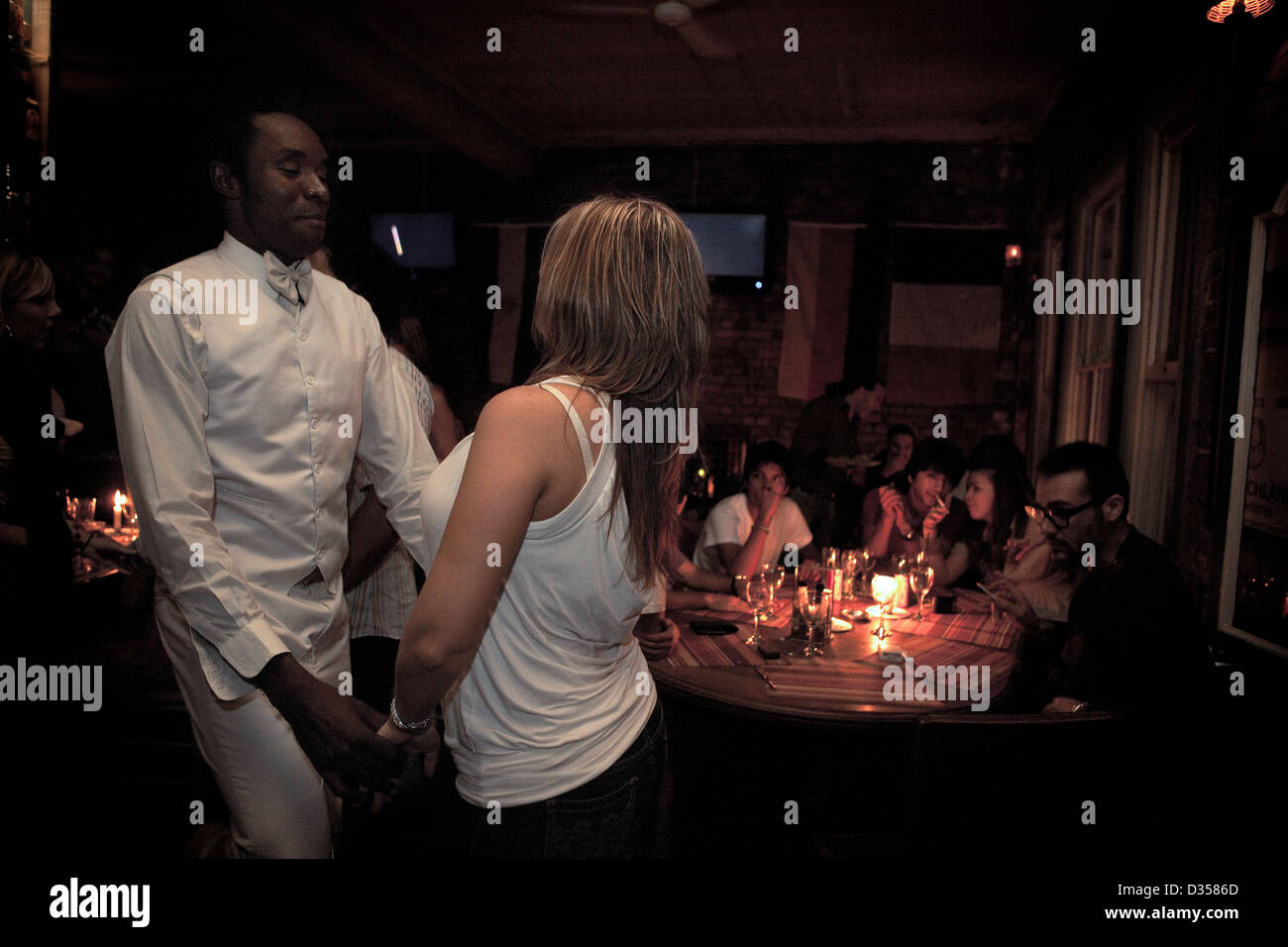 Two salsa dancers in the early hours of the morning while others sit by ...