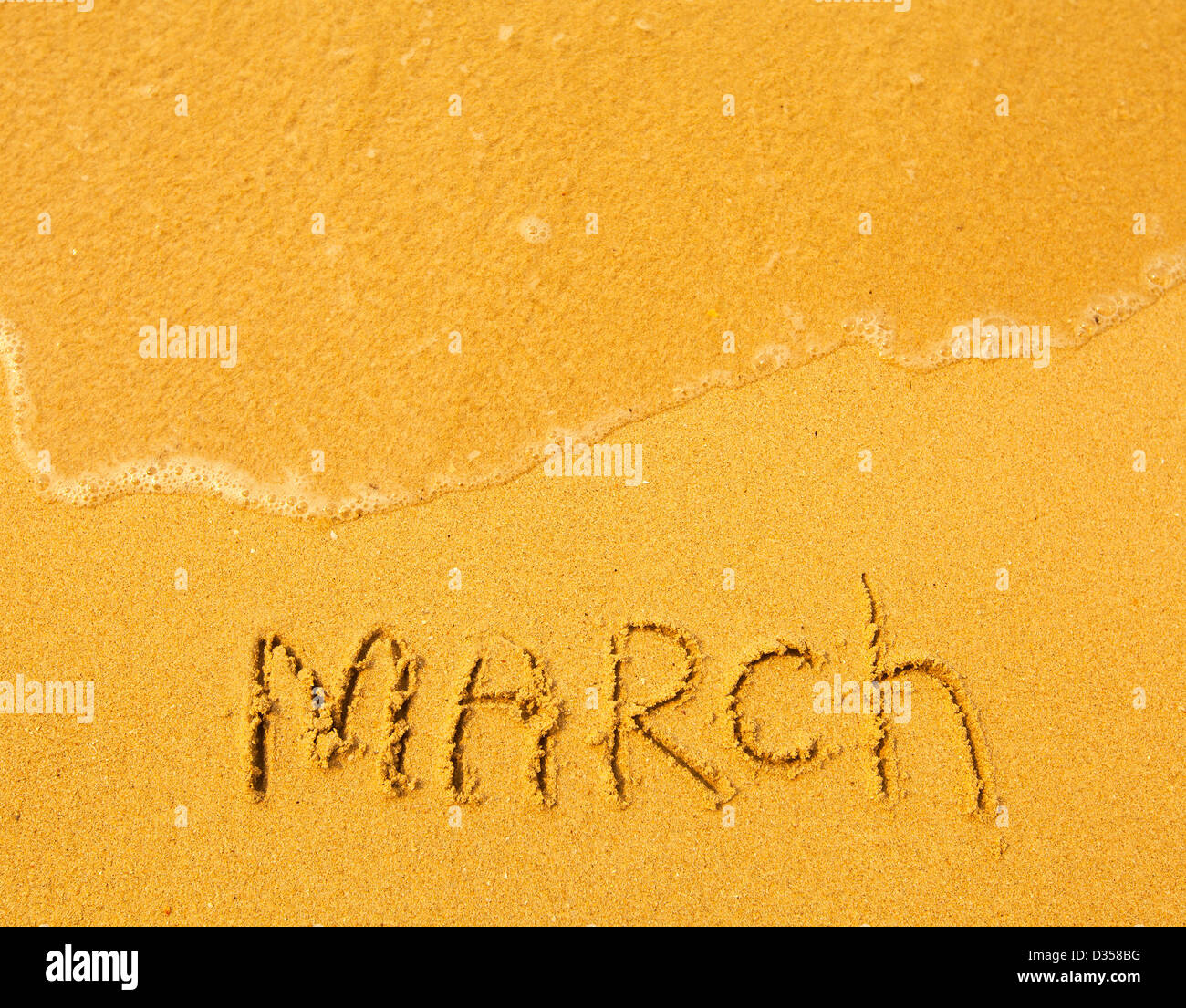 March - written in sand on beach texture - soft wave of the sea (months ...