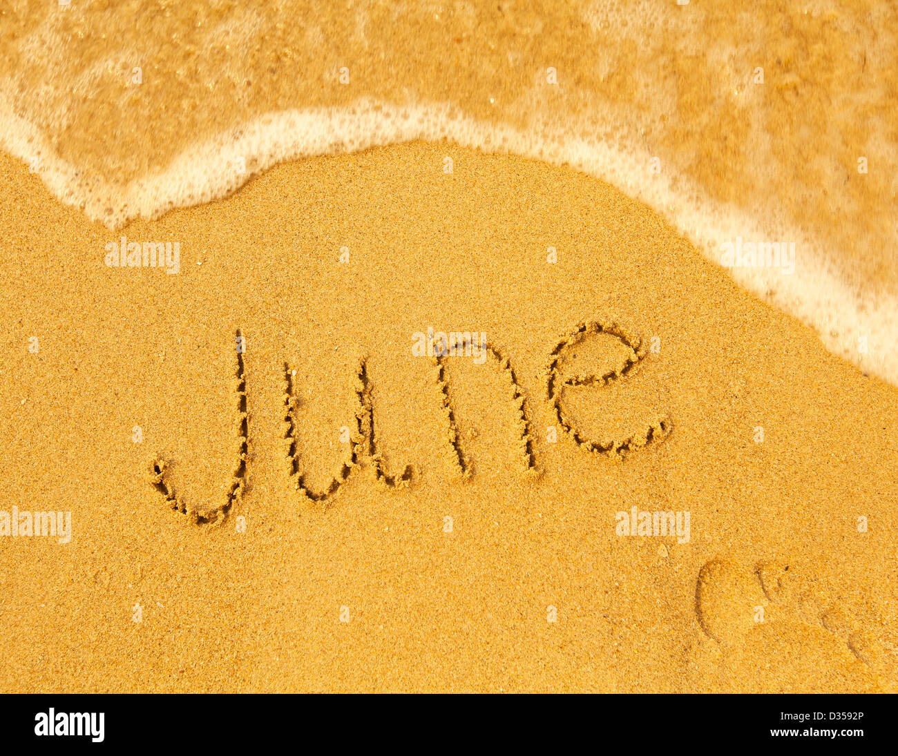 June - written in sand on beach texture - soft wave of the sea (months ...