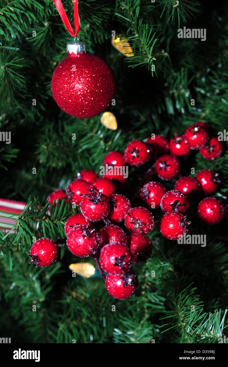 red holiday berries and ornaments on a lit Christmas tree Stock Photo ...