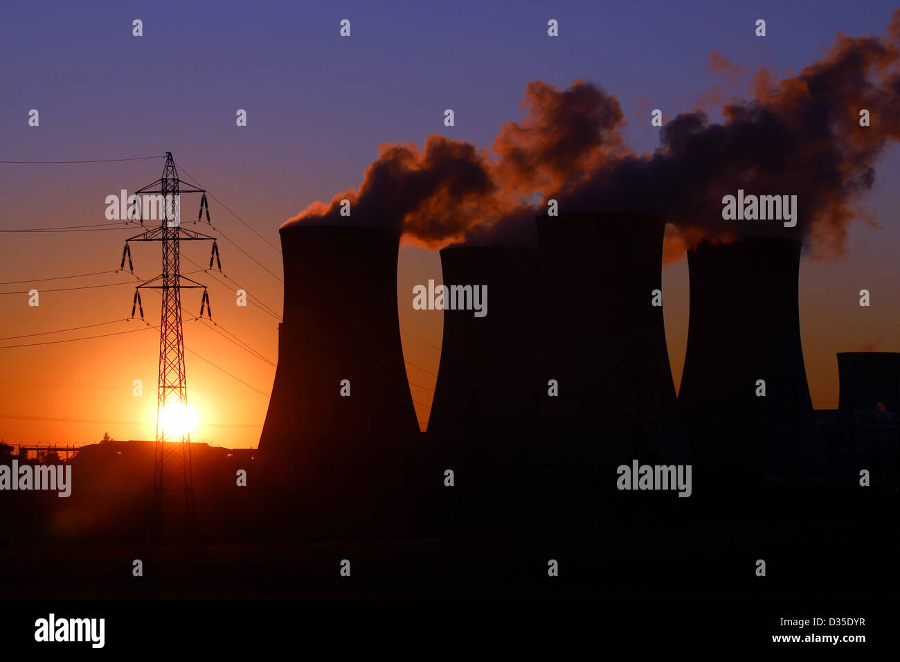 high voltage tower and power plant chimney during sunset Stock Photo ...
