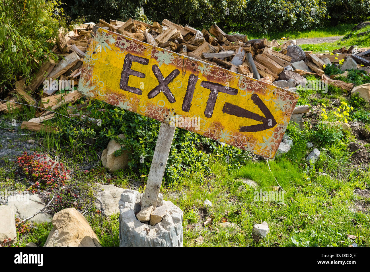 An exit sign pointing down toward the ground, hand painted in yellow ...