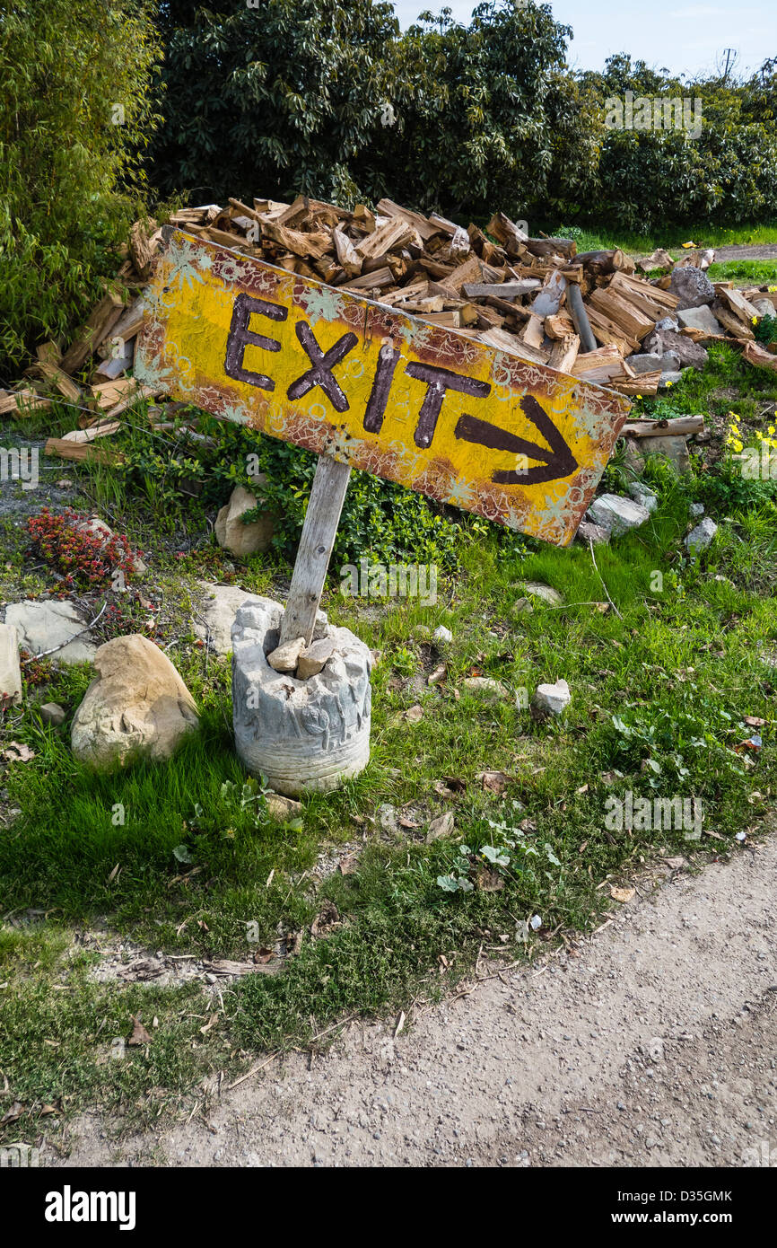 An exit sign pointing down toward the ground, hand painted in yellow ...