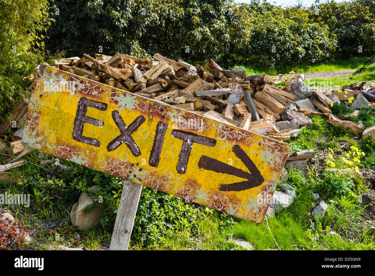 An exit sign pointing down toward the ground, hand painted in yellow ...