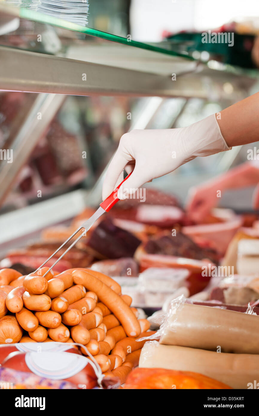 Butcher picking fresh and tasty sausages for selling at shop Stock ...