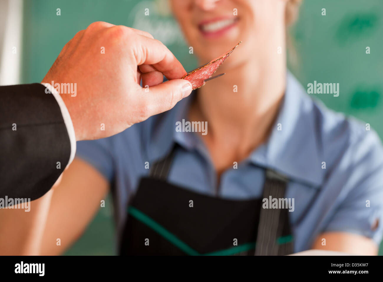 Male customer taking a piece of meat from butcher at butchery Stock ...