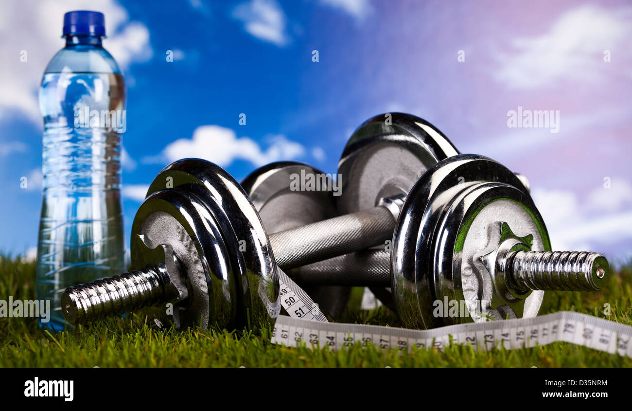 Measuring of dumbbell on green grass Stock Photo - Alamy