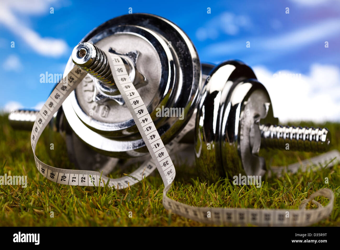 Measuring of dumbbell on green grass Stock Photo - Alamy