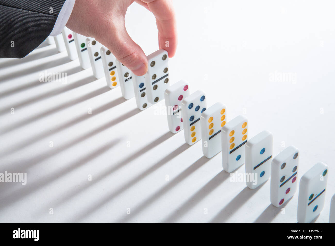 Hand placing domino into line of dominoes Stock Photo - Alamy