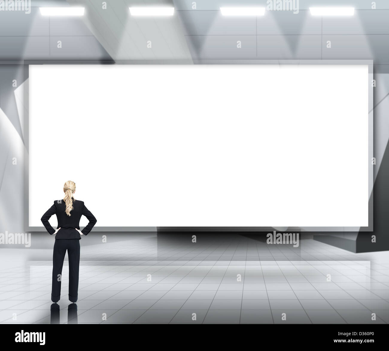 Businesswoman looking up at large blank screen under lights Stock Photo ...