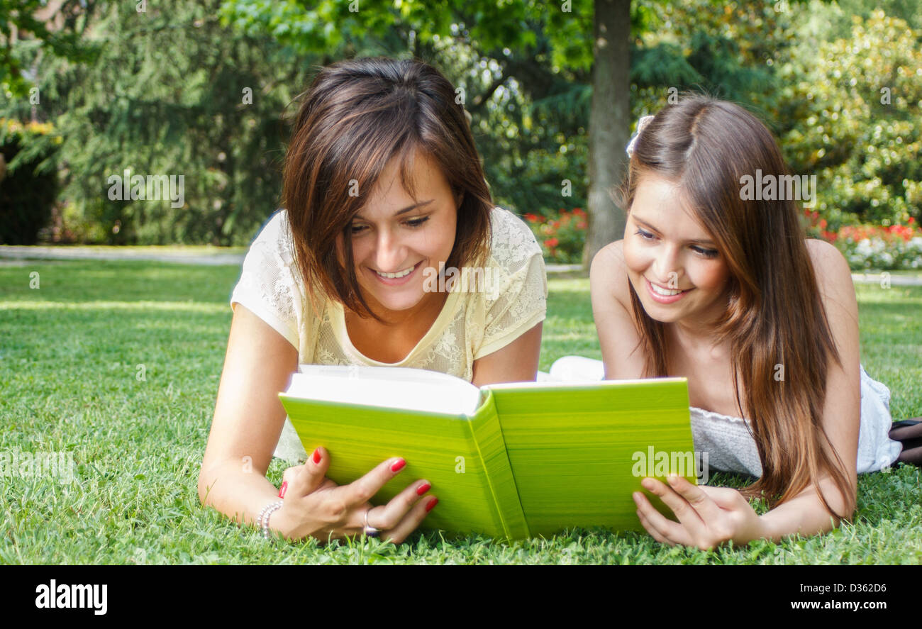Two beautiful students reading a book on the grass Stock Photo - Alamy