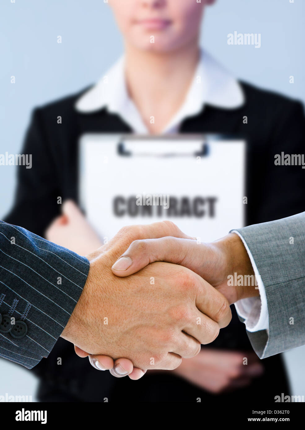 Businessmen shaking hands with contract behind them Stock Photo - Alamy