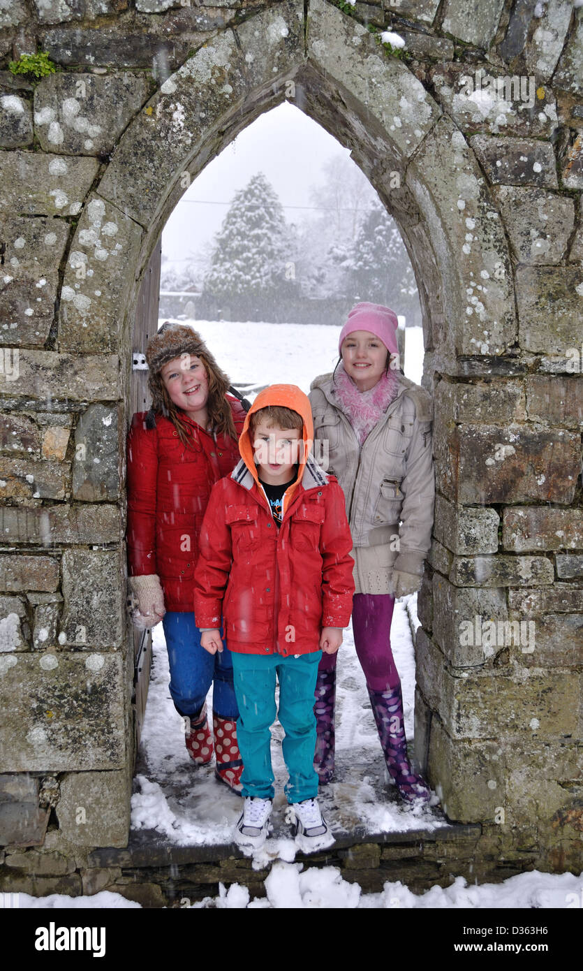 Children sheltering in churchyard archway from snow Stock Photo - Alamy
