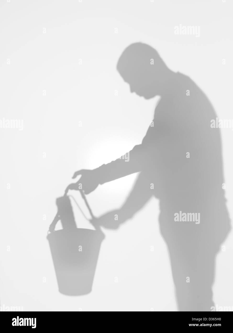 side view of man holding a bucket in his hands and dipping a paint ...