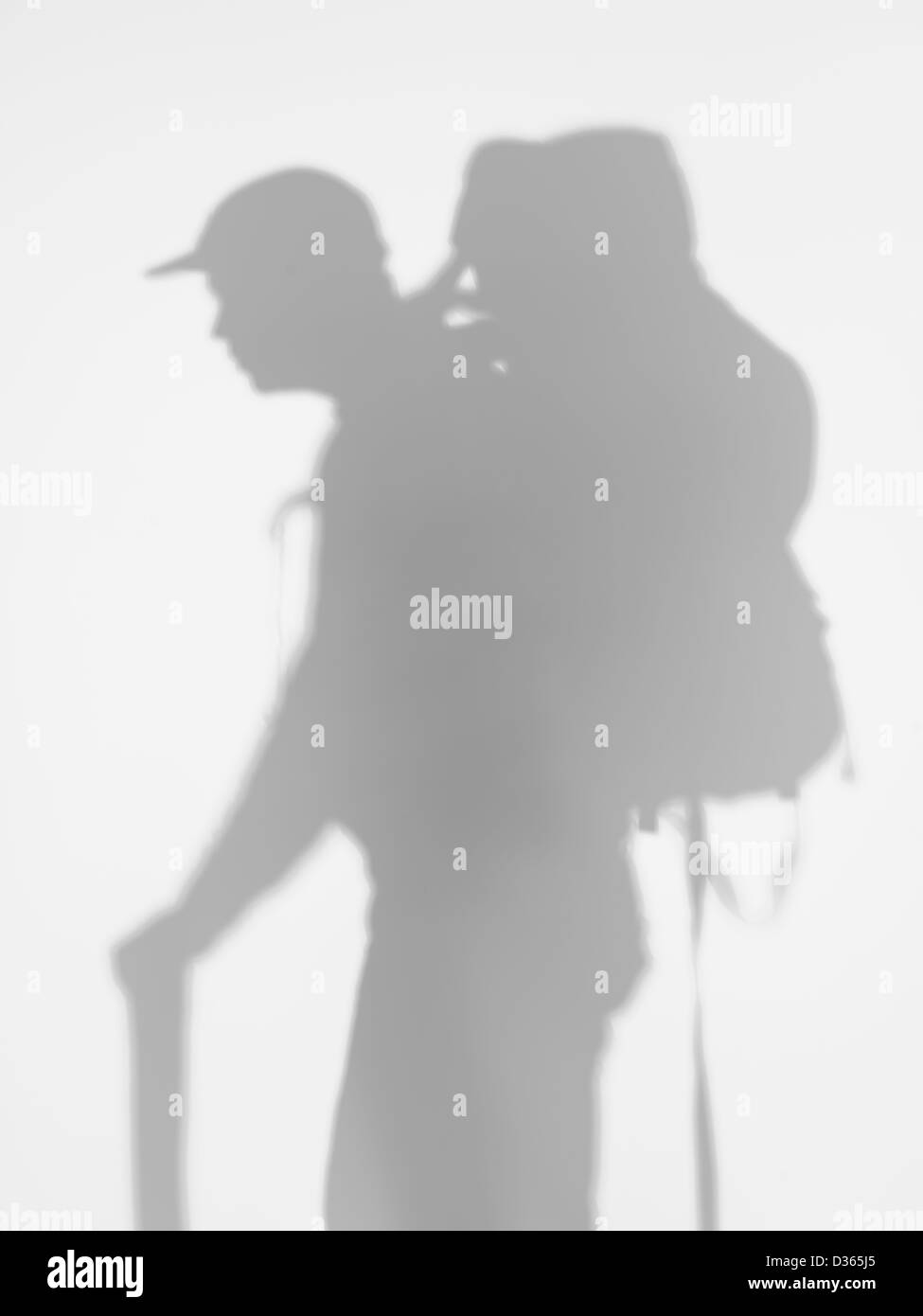 side view of man with backpacker, cap and a hiking stick behind a ...