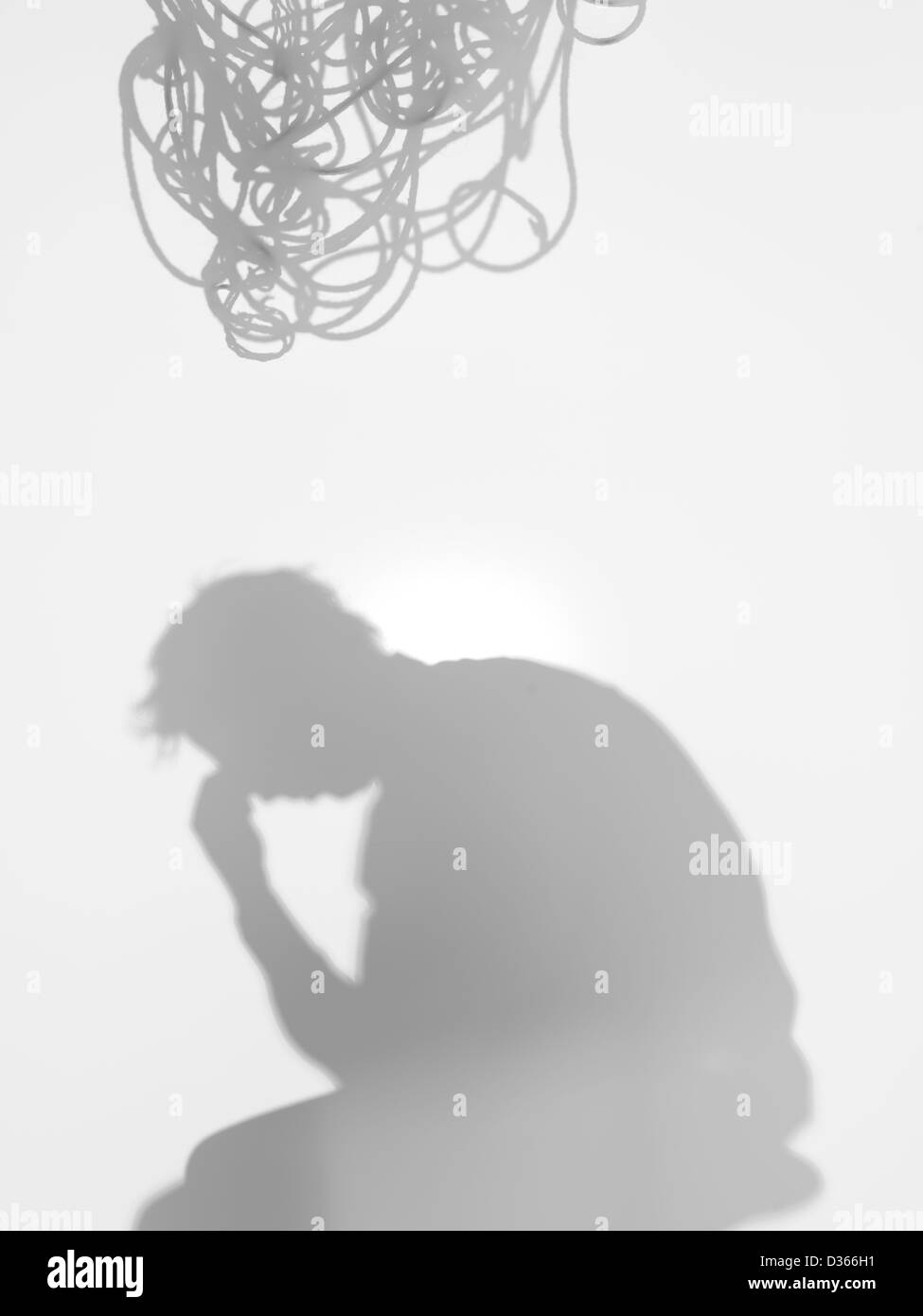 side view of man sitting with a thinking gesture, with tangled rope on ...