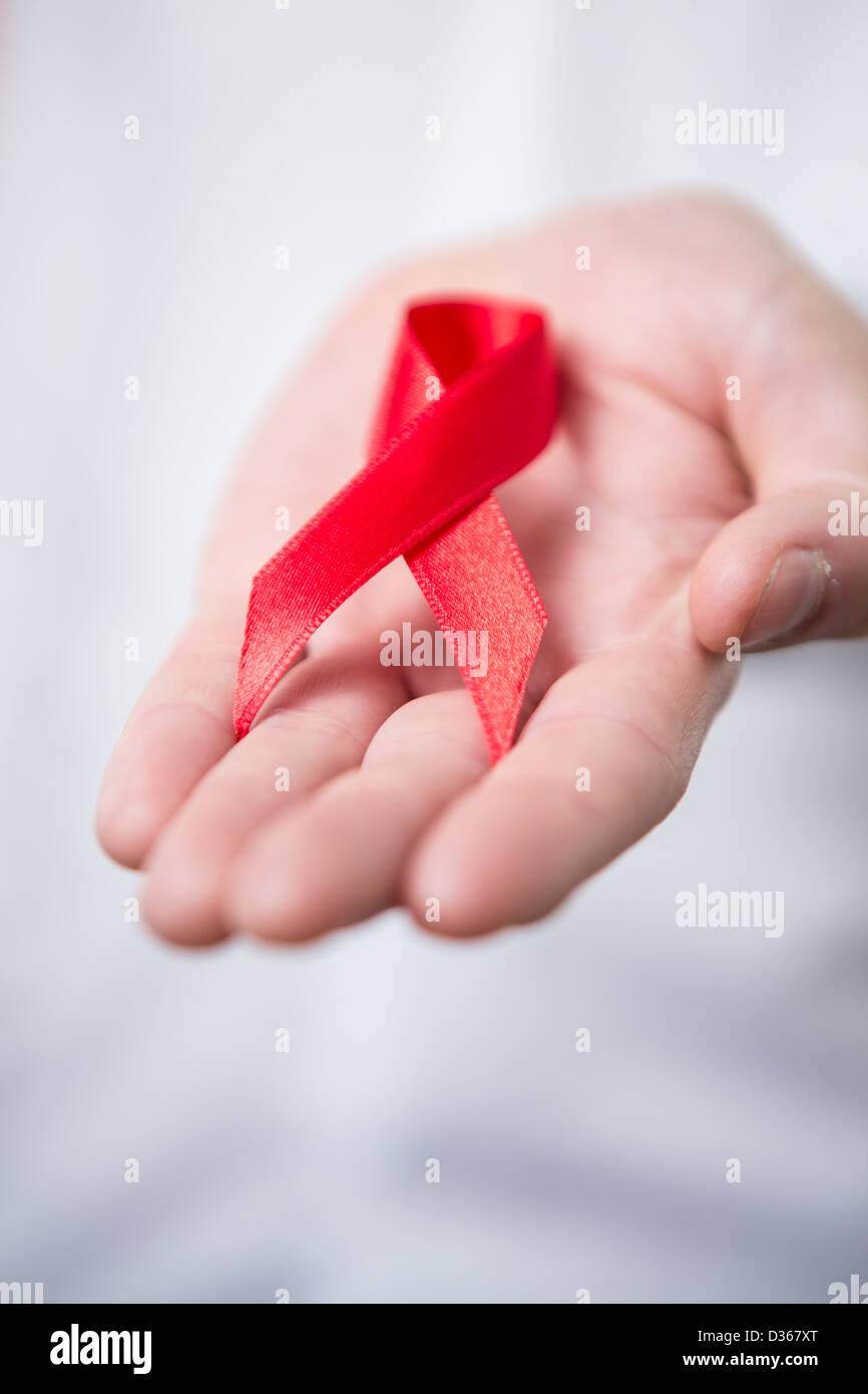 Man holding out red aids awareness ribbon Stock Photo - Alamy