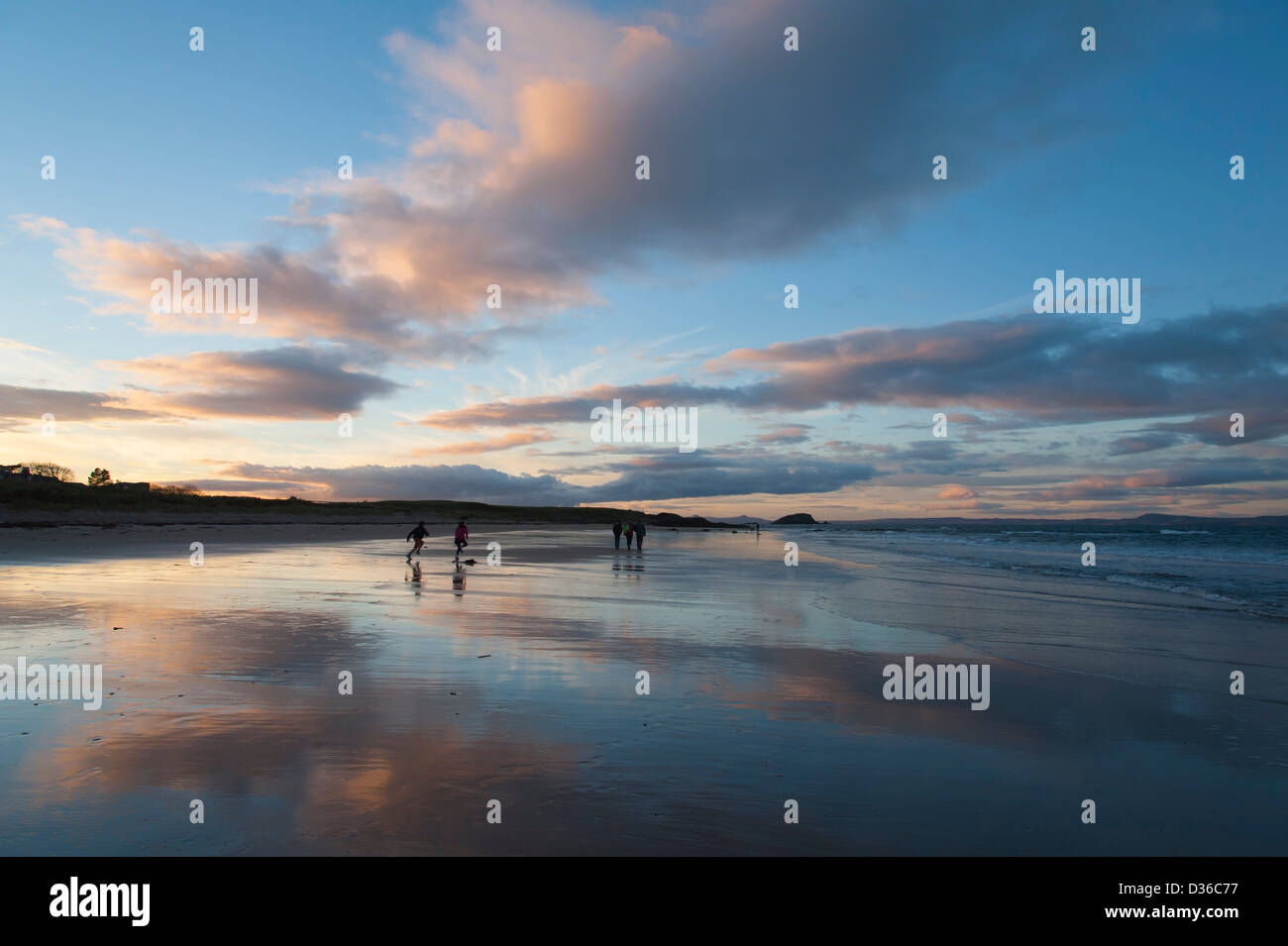 A family walking across the beach at sunset at North Berwick, East ...