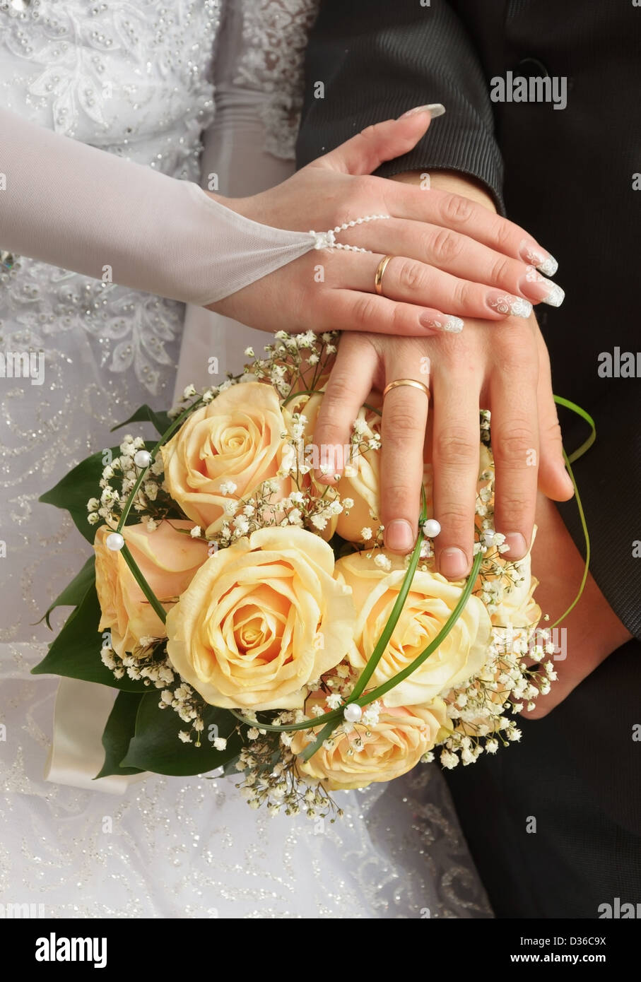 A newly wed couple place their hands on a wedding bouquet Stock Photo ...