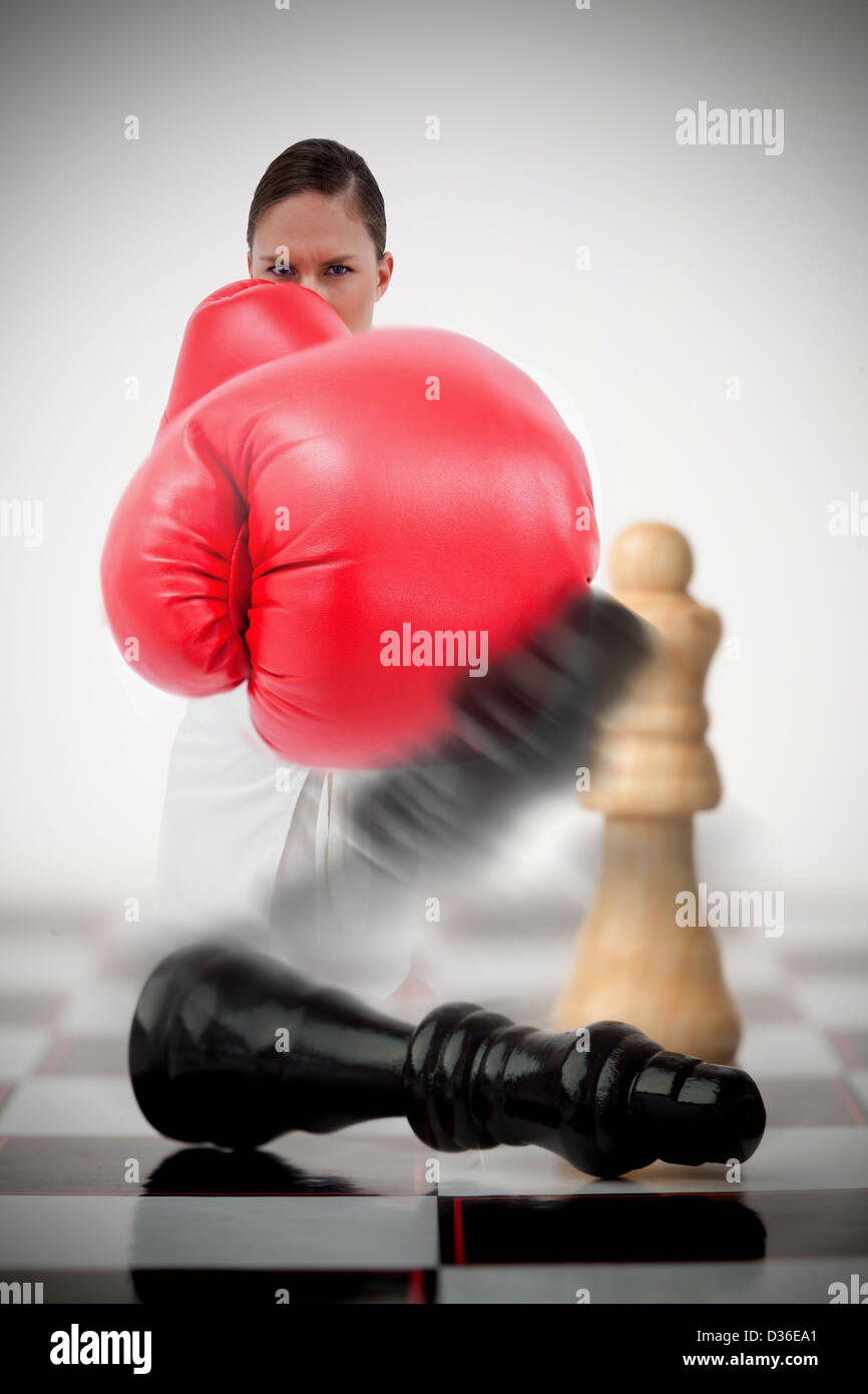 Woman in boxing gloves knocking over chess pieces Stock Photo - Alamy