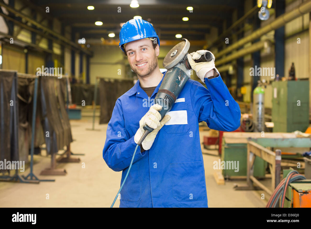Construction worker with helmet and angle grinder posing in assembly ...