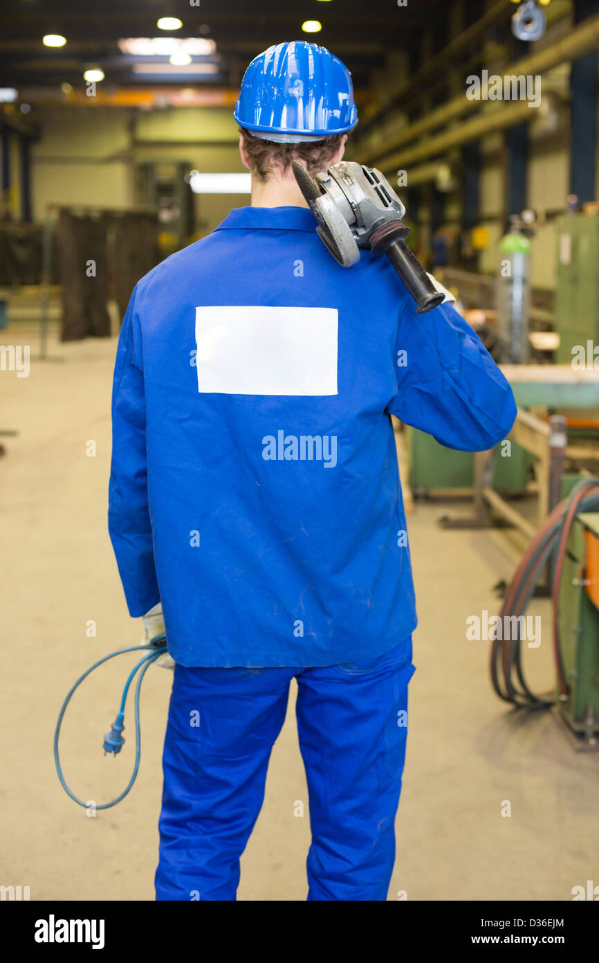 Construction worker with helmet and angle grinder posing in assembly ...