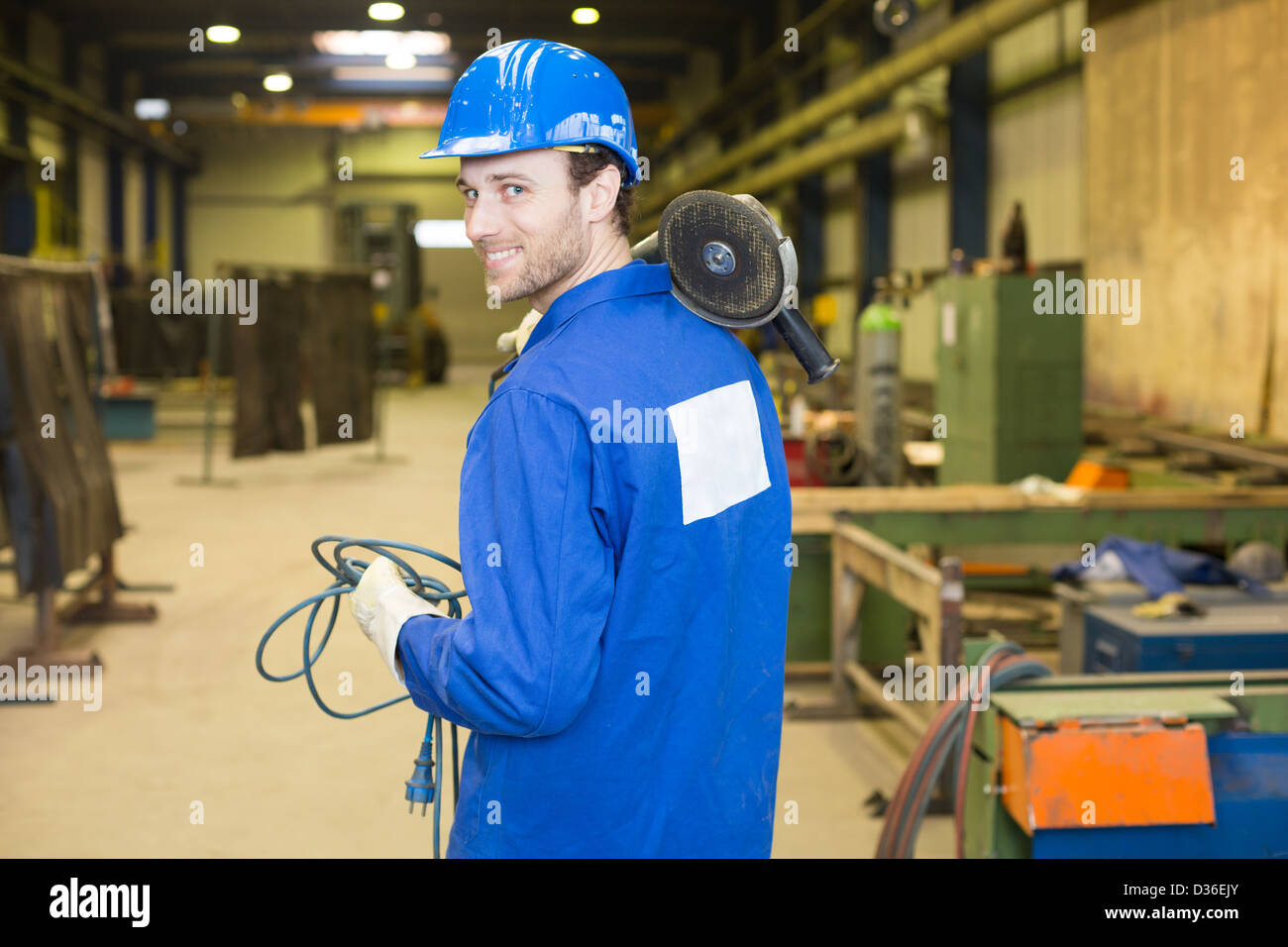 Construction worker with helmet and angle grinder posing in assembly ...