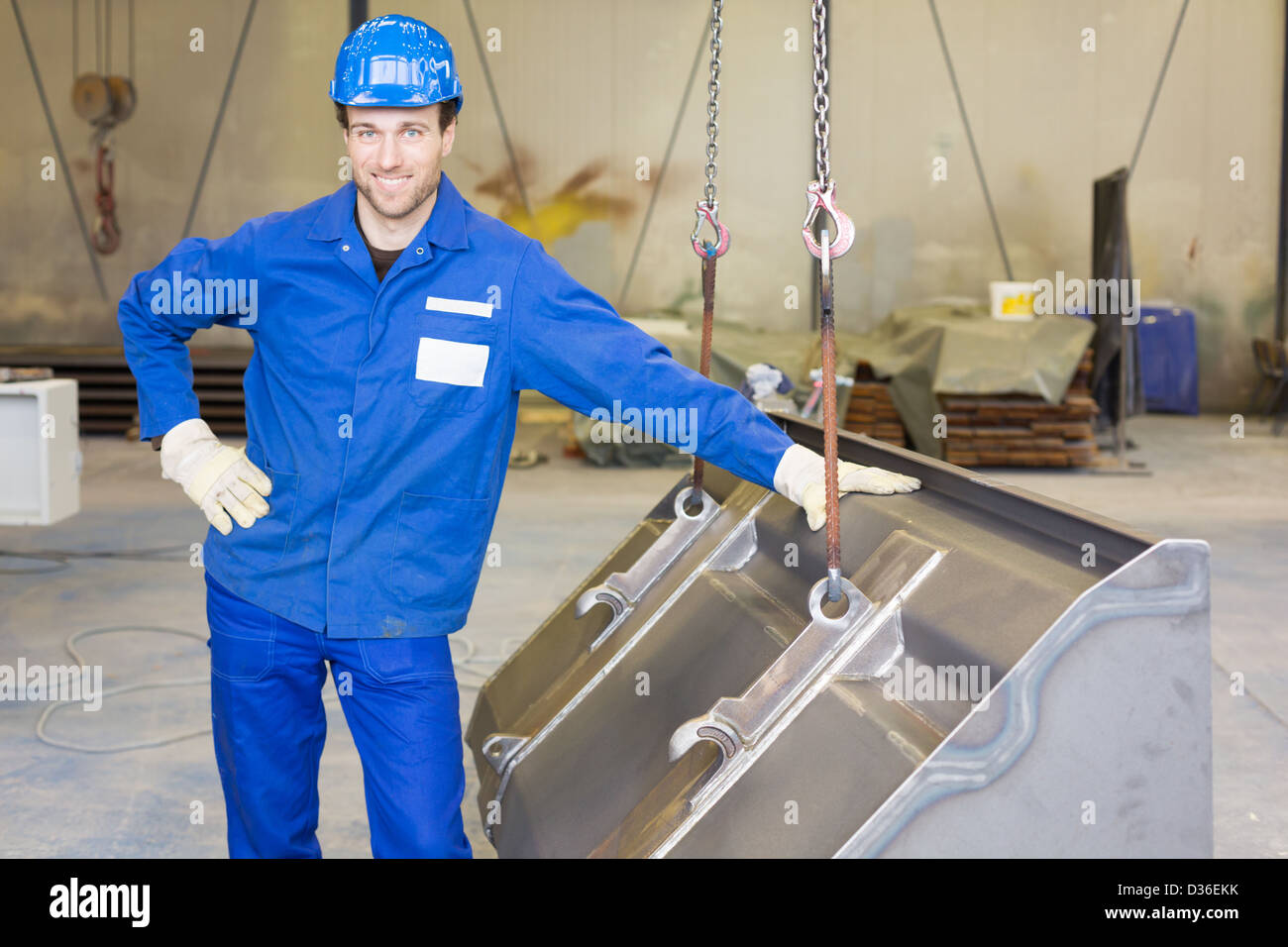 Construction worker standing next to bucket Stock Photo - Alamy