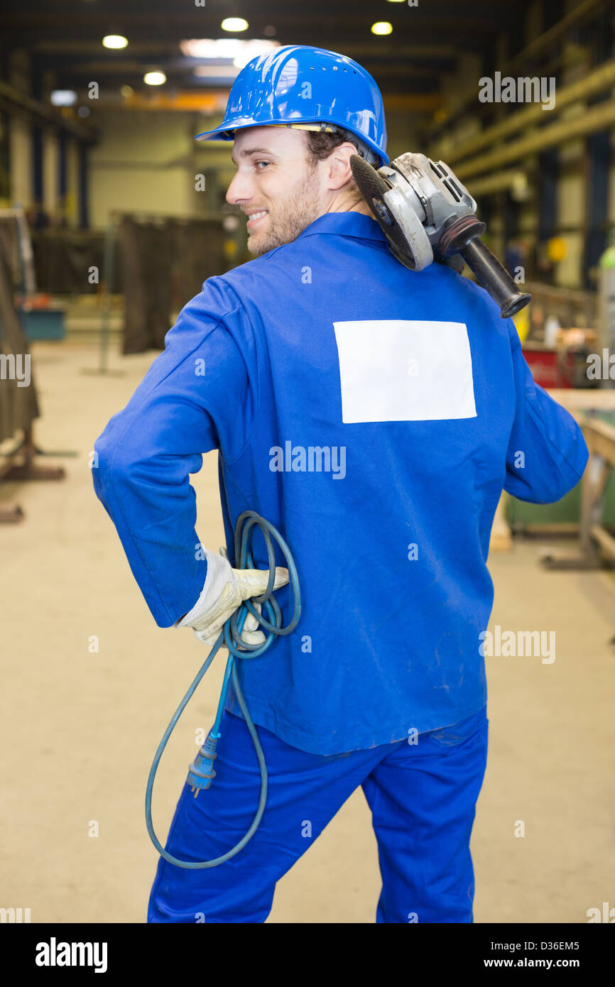 Construction worker with helmet and angle grinder posing in assembly ...