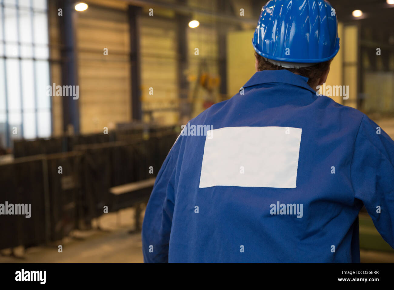 Construction worker looking at assembly hall or factory Stock Photo - Alamy