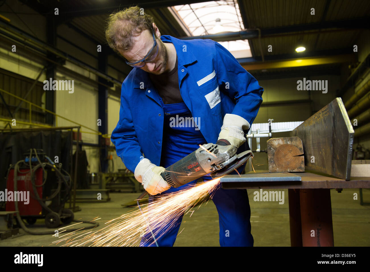 A construction worker using an angle grinder producing a lot of sparks ...