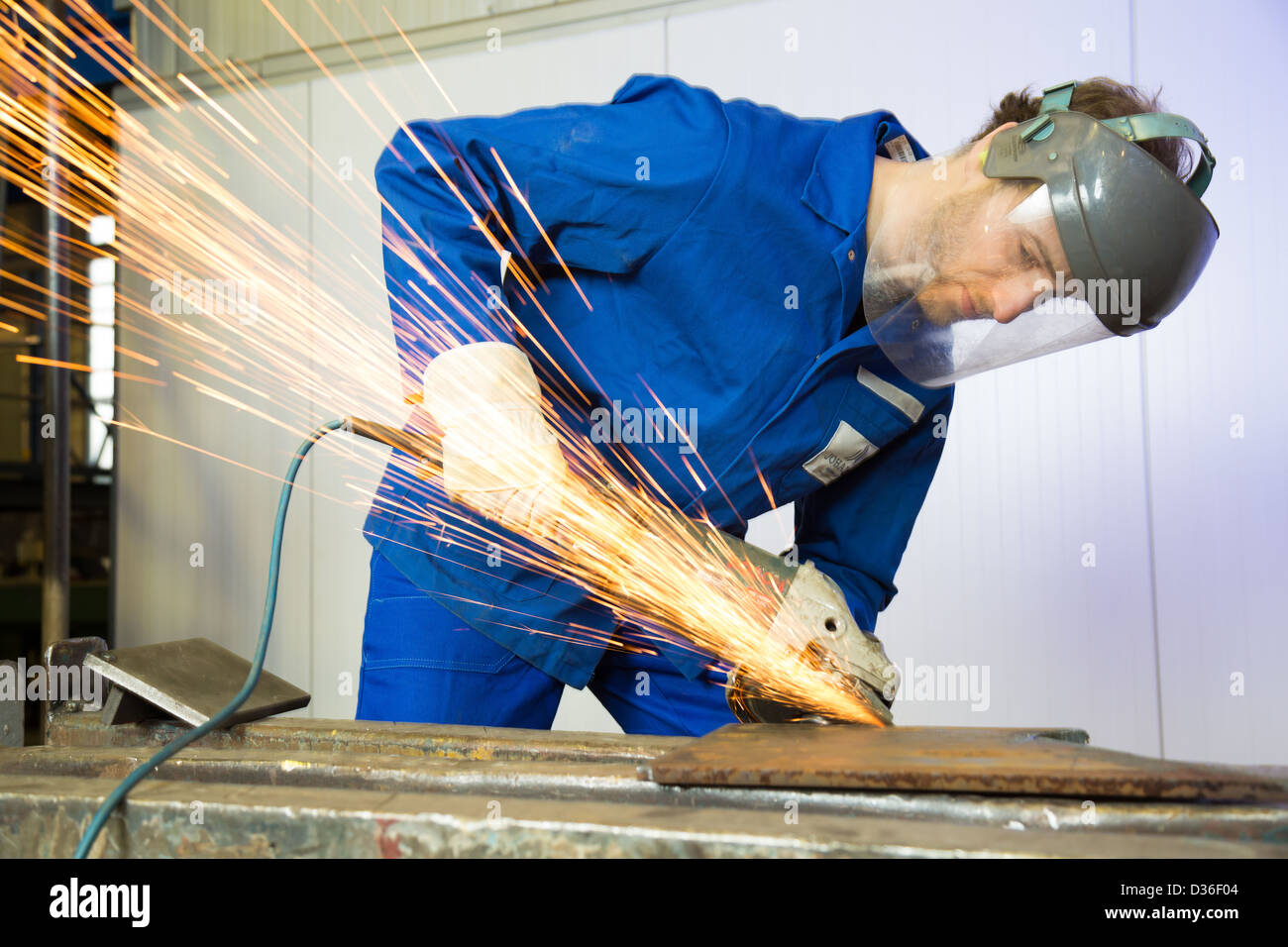 A construction worker using an angle grinder producing a lot of sparks ...