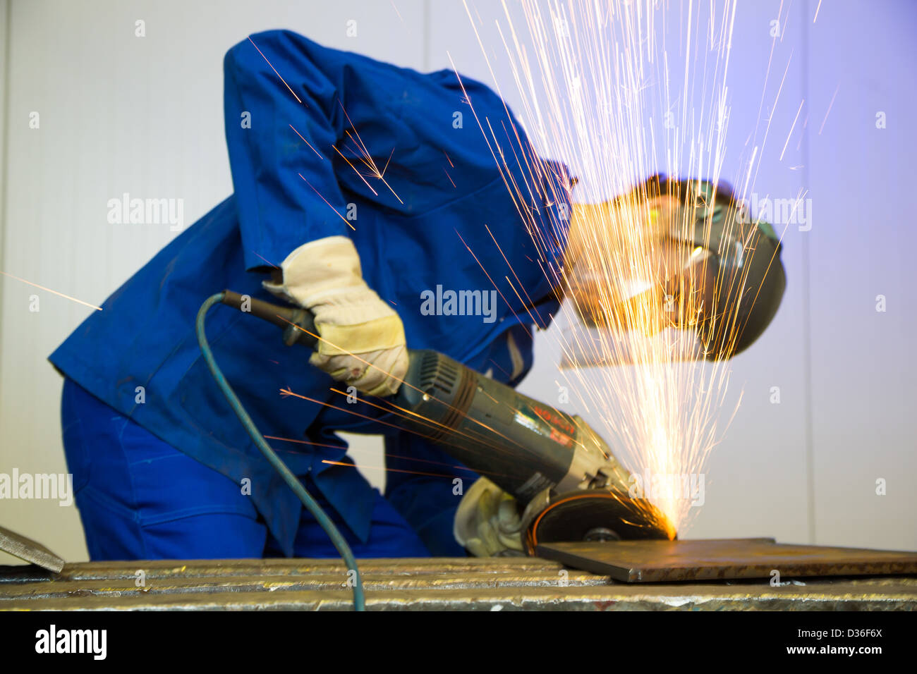 A construction worker using an angle grinder producing a lot of sparks ...