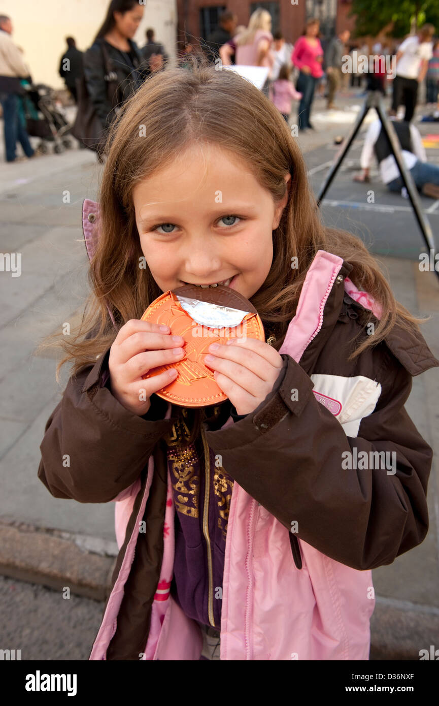 Young girl eating large chocolate coin happy Stock Photo - Alamy
