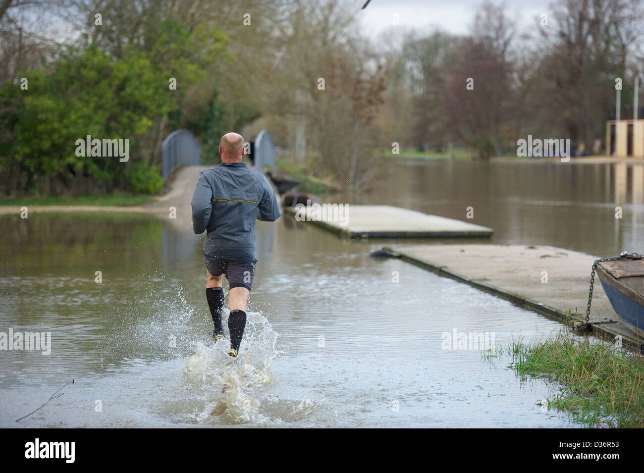 Man running through flooded path next to the River Thames in Oxford ...