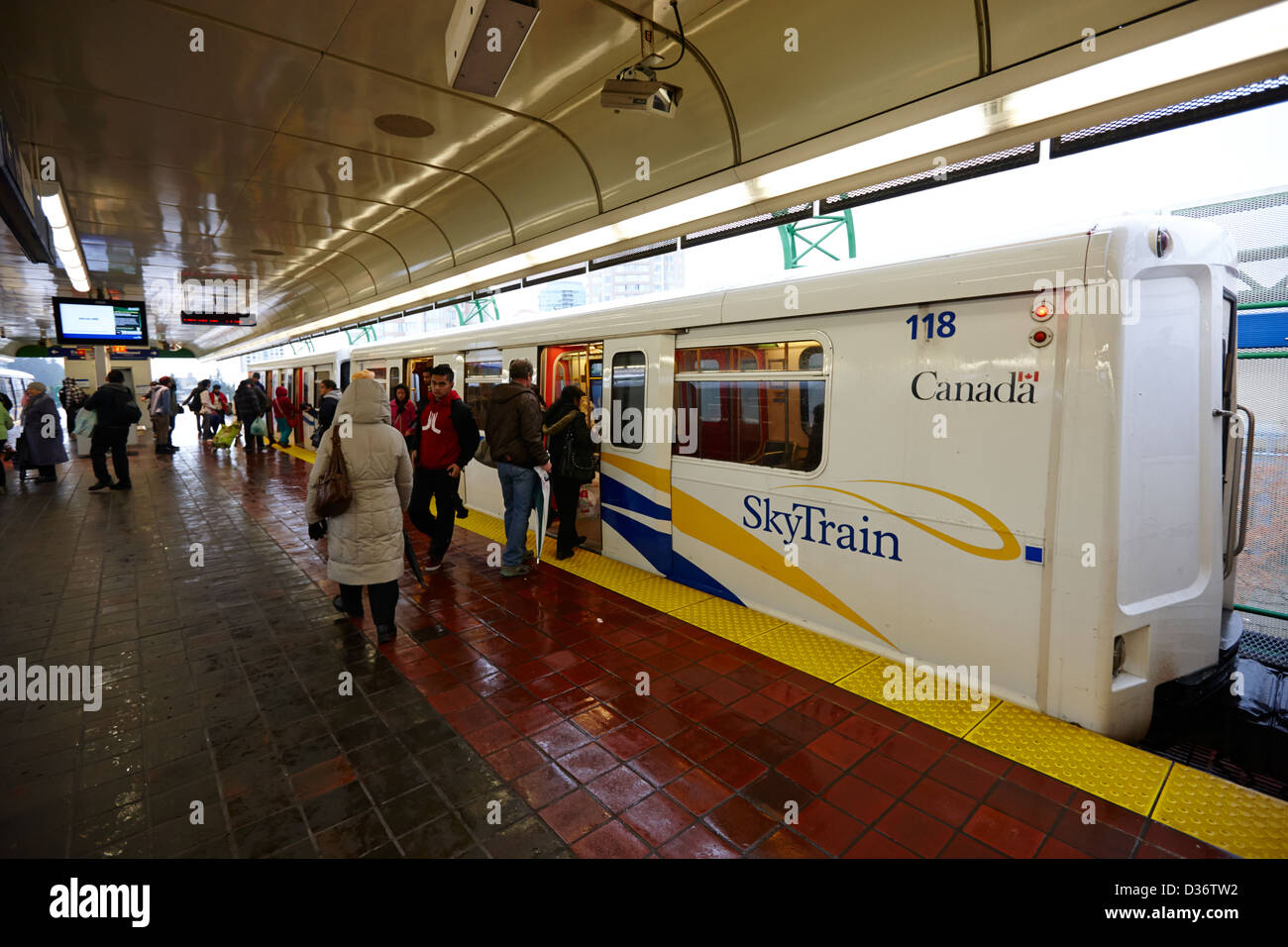 passengers boarding canada line skytrain overground station on wet day ...