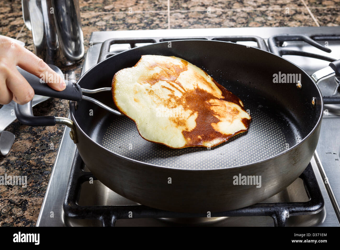 Horizontal photo of main focus on pancake being flipped in hot frying ...