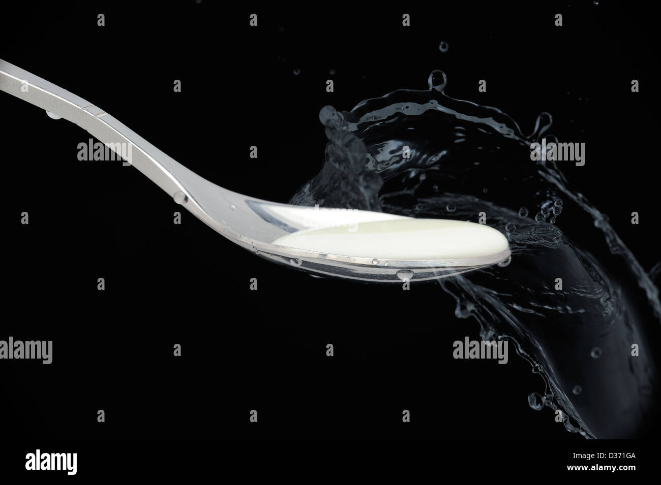 Silver Teaspoon with full cream milk in isolated black background Stock ...