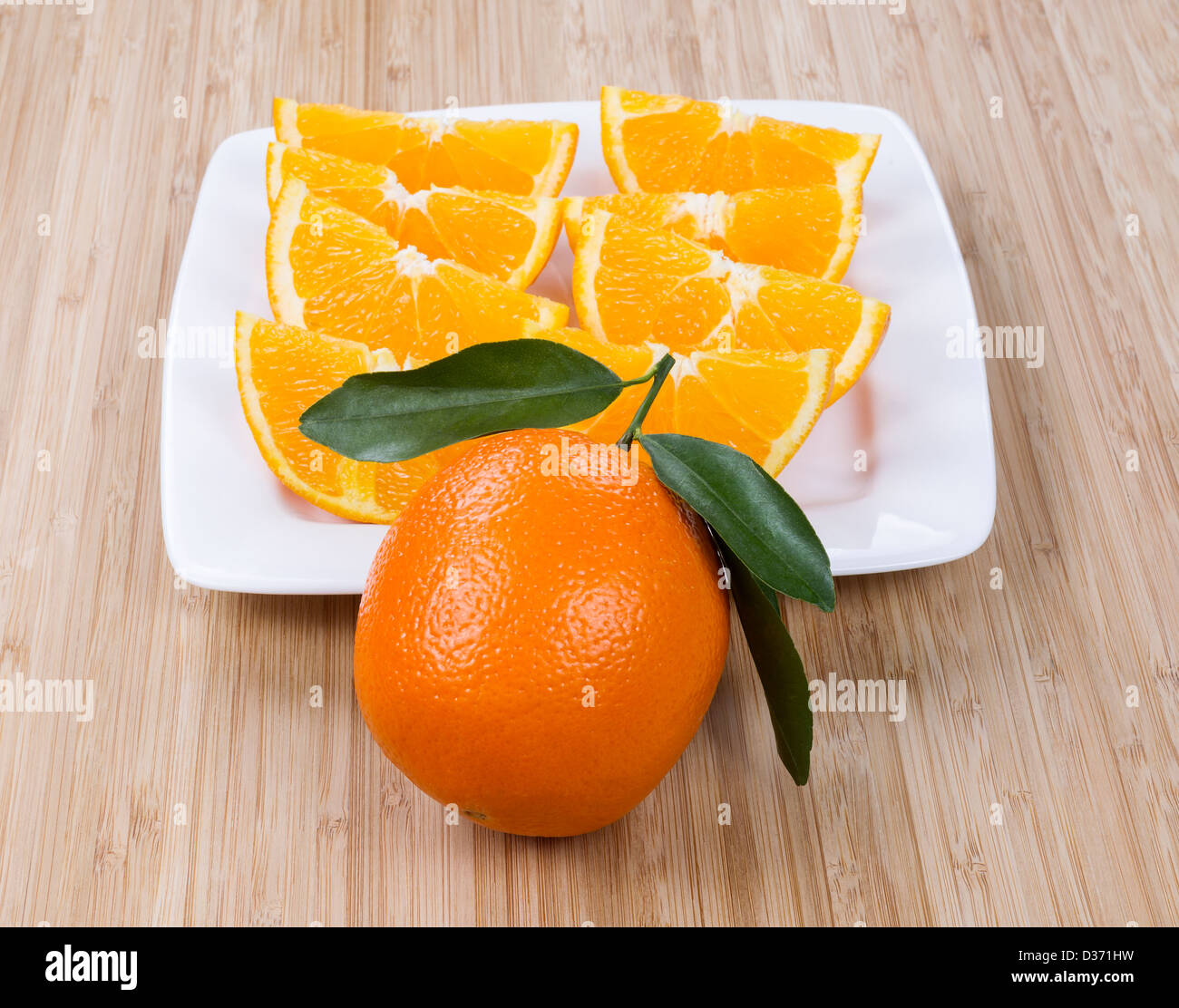 photo of whole and sliced ripe orange pieces on white plate with ...