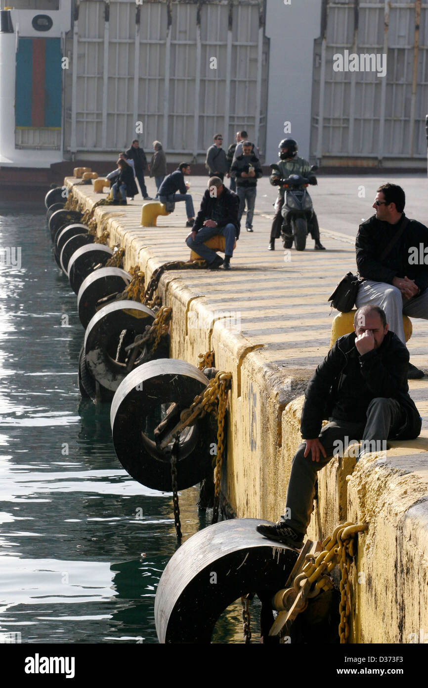 Men sit on a dock at Piraeus harbour Greece Stock Photo - Alamy
