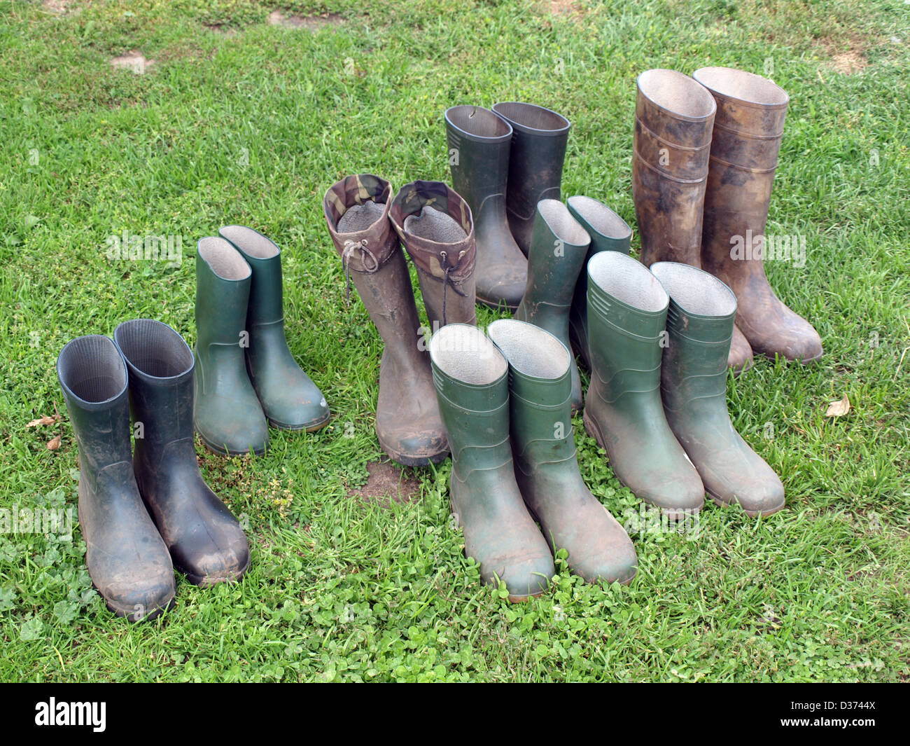Lot on dirty rubber boots on grass, for washing Stock Photo - Alamy