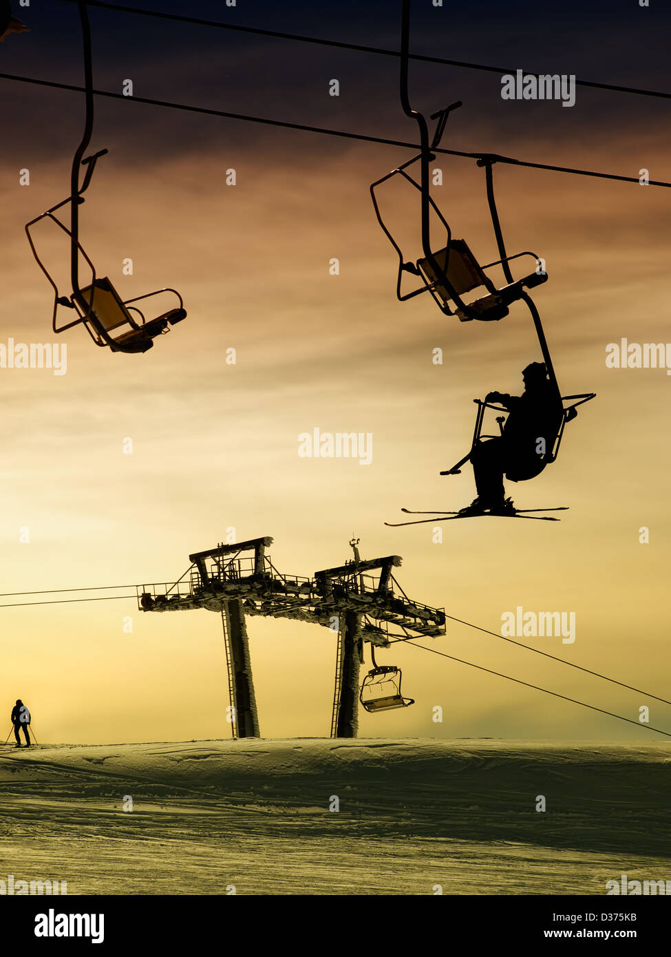 Silhouette of a skier on the ski lift above ski slopes at sunset Stock ...