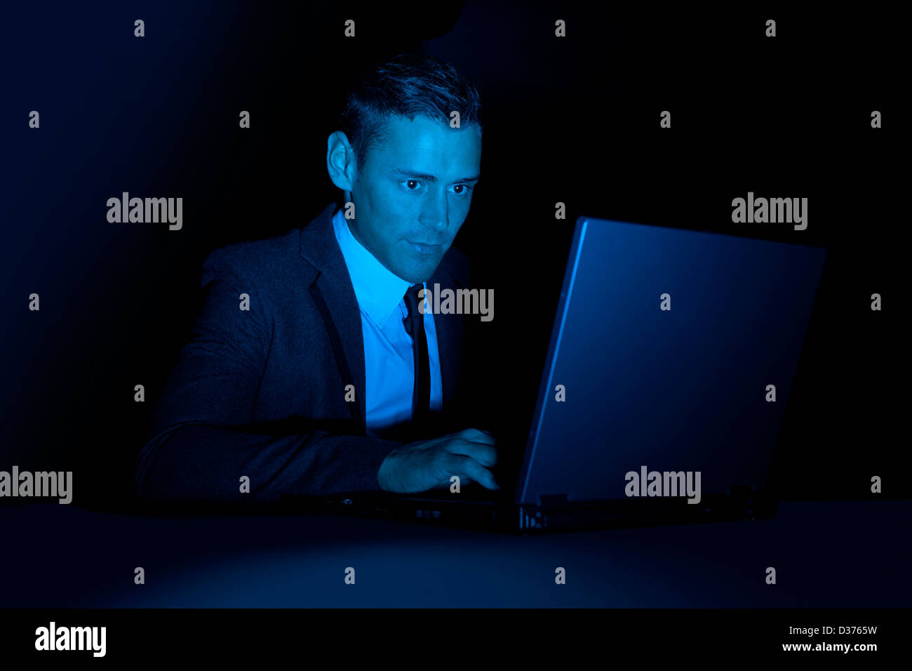 A man working on a laptop computer in the dark Stock Photo - Alamy