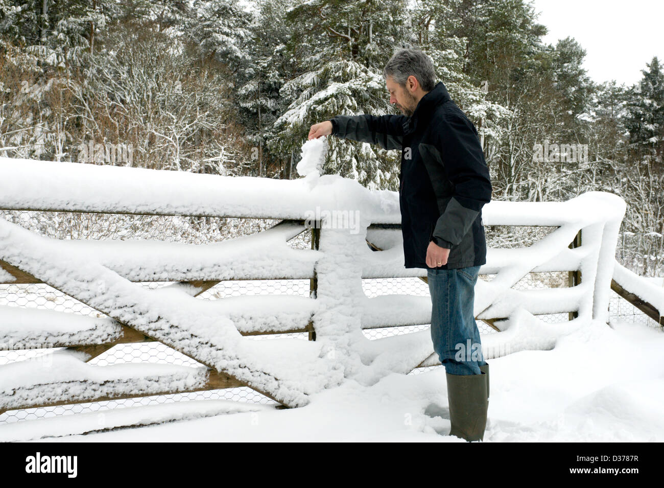 A man struggles to open a snow covered gate after heavy overnight snow ...