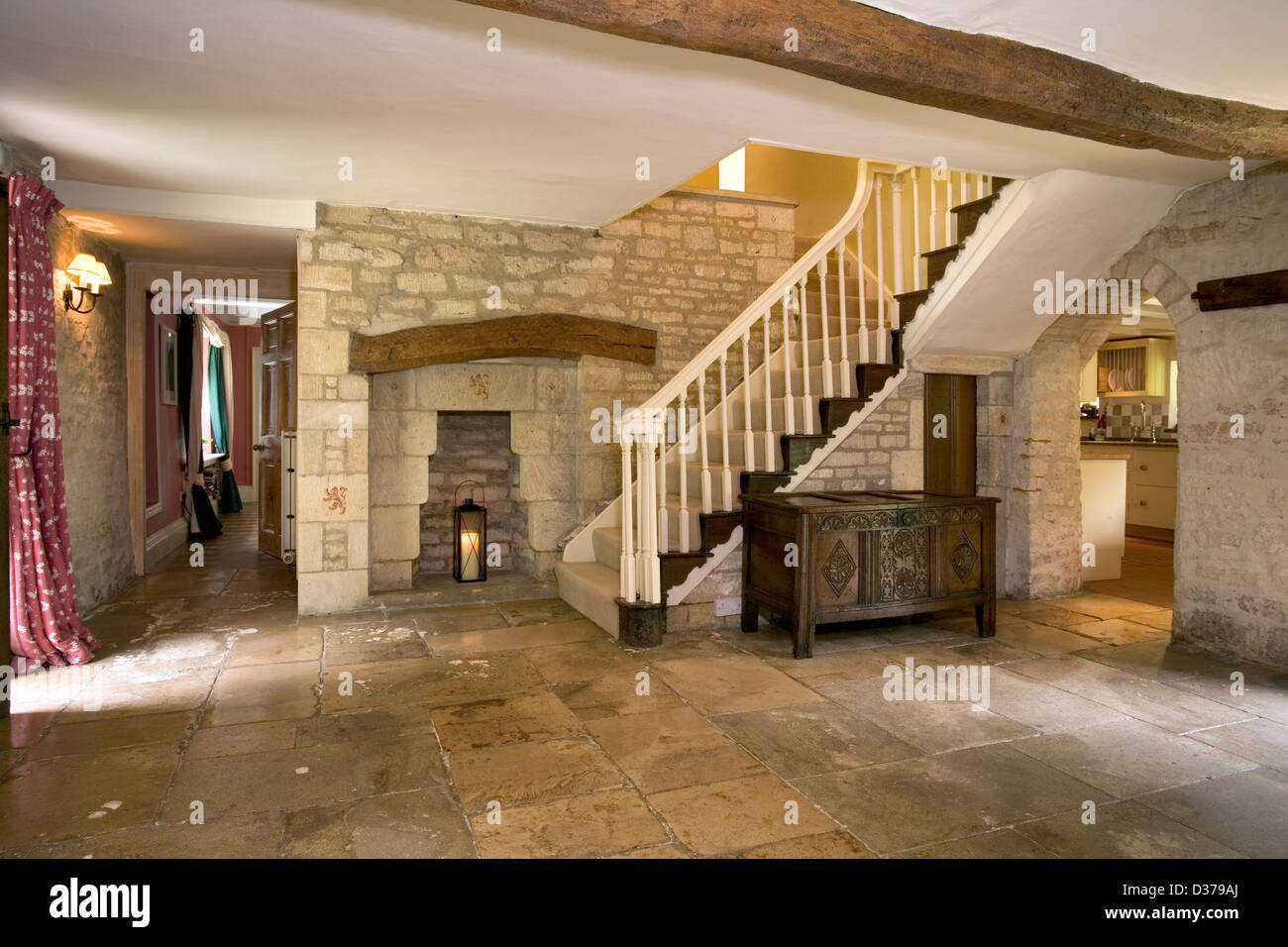 A large old entrance hall with bare stone walls and a flagstone floor ...