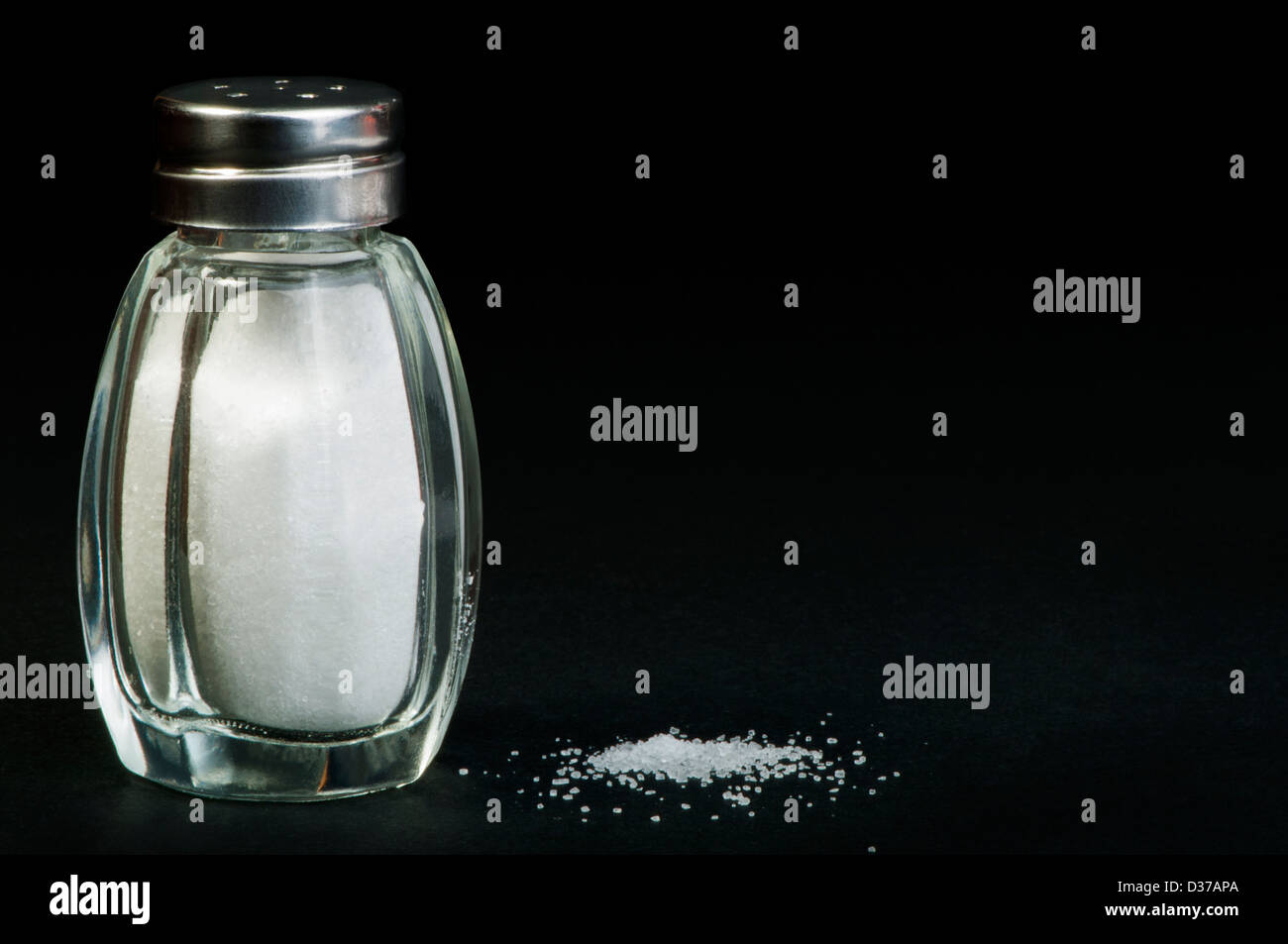 Pile of spilled salt and saltshaker black isolated Stock Photo - Alamy