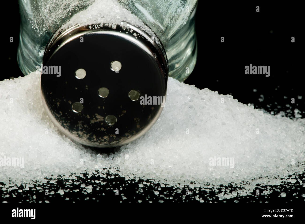 Pile of spilled salt and saltshaker black isolated Stock Photo - Alamy