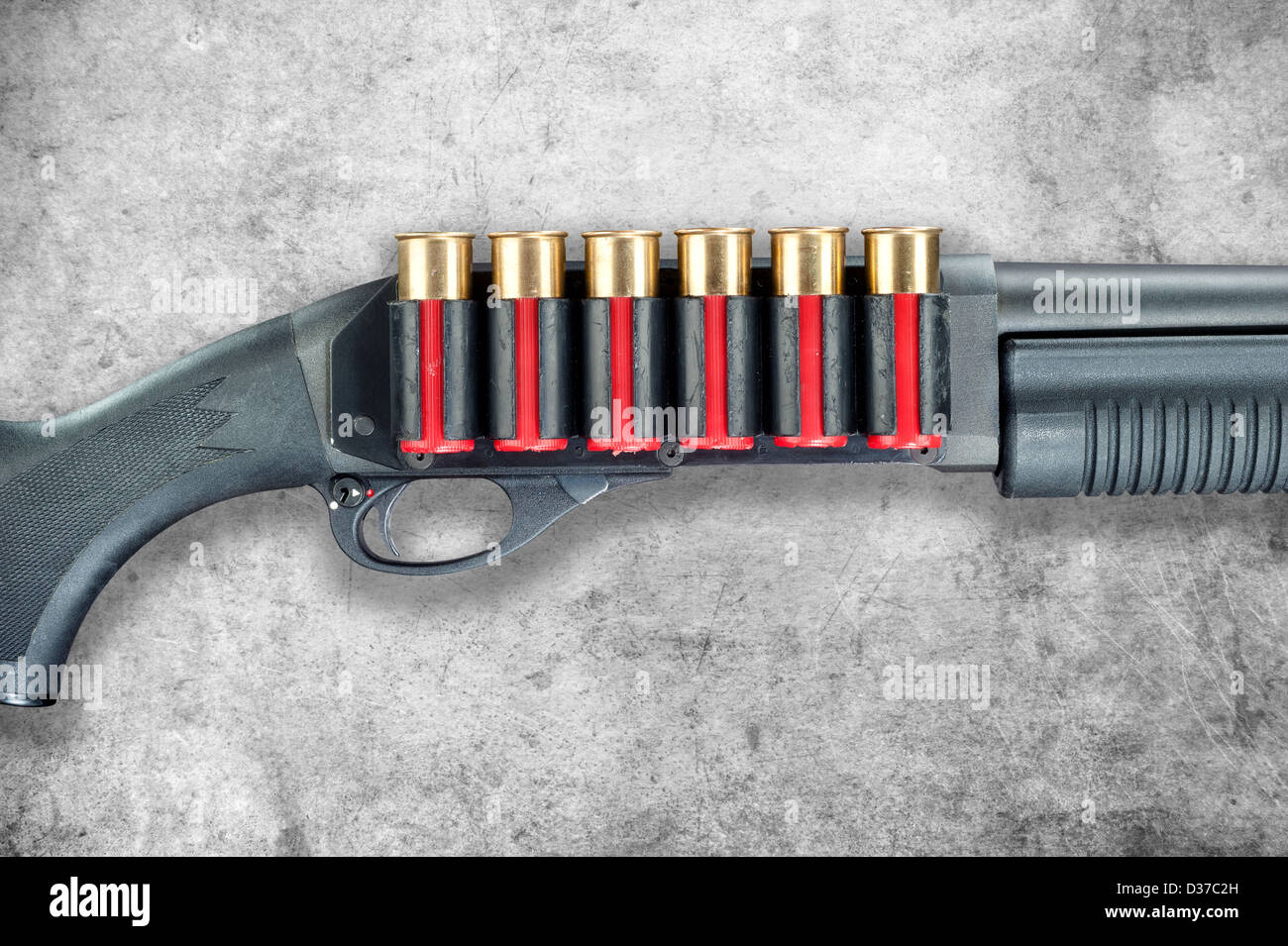 A shotgun with red shell cartridge ammo isolated against a grunge gray ...